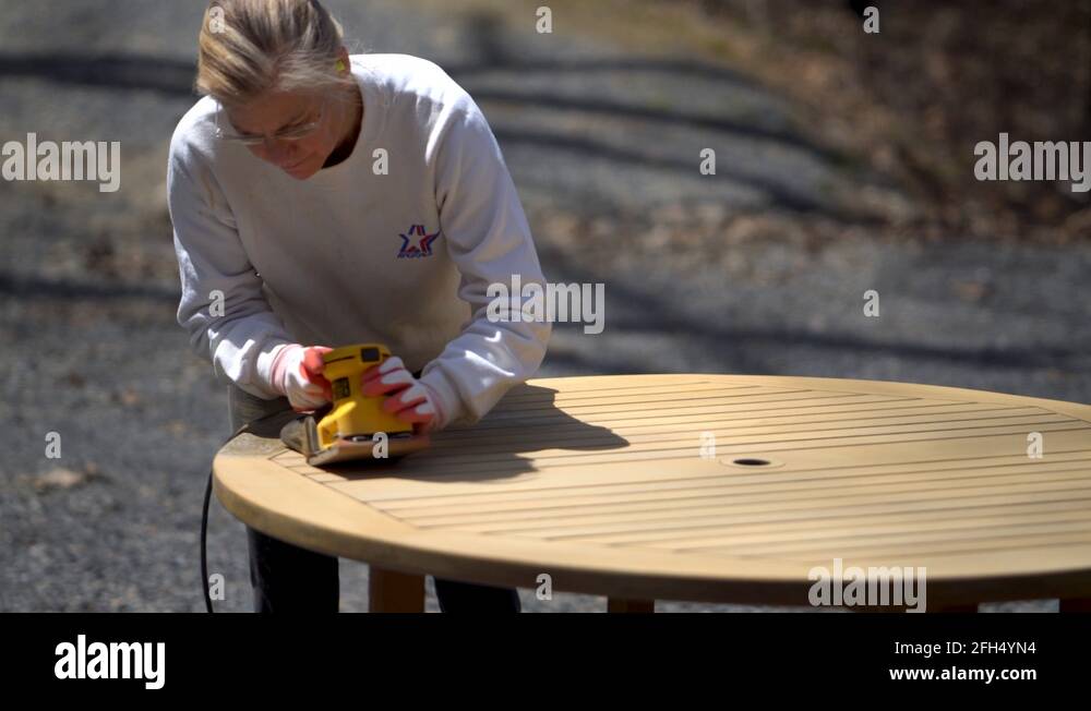 Woman turns sander on edge to sand angled parts of table top Stock ...