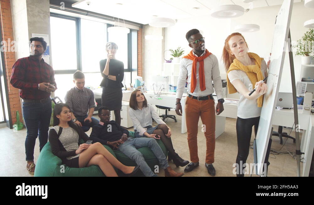 Young nice ginger female is building up graphs on the flip chart Stock ...