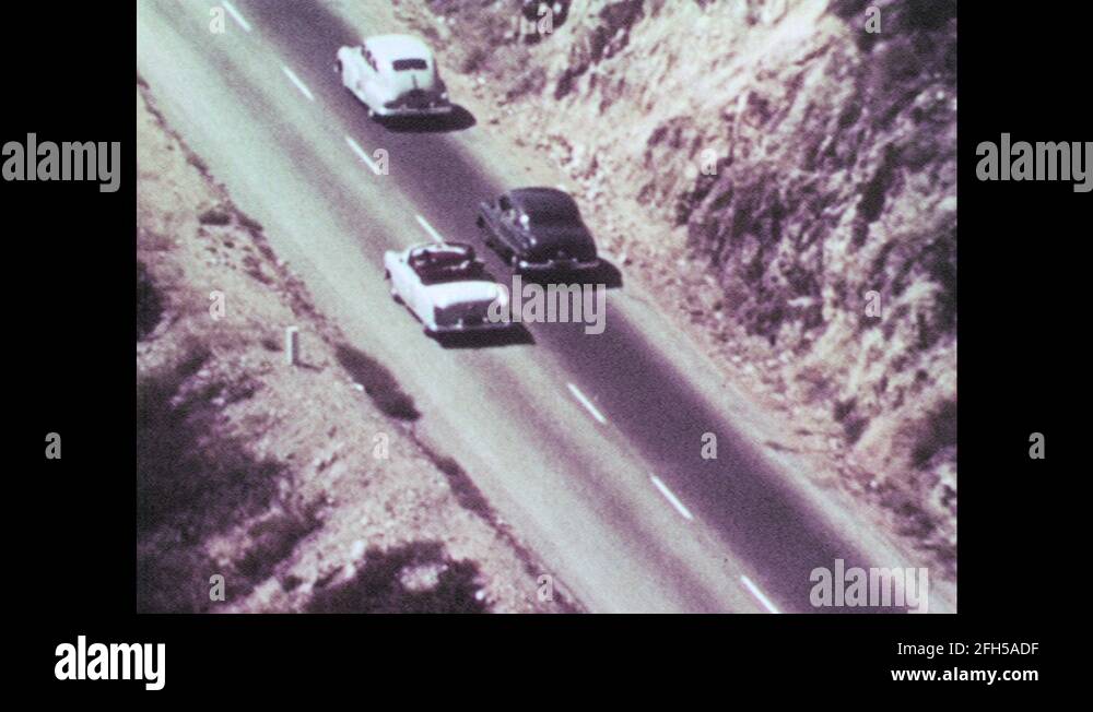 1950s: UNITED STATES: overhead view of car on mountain road. Front view ...