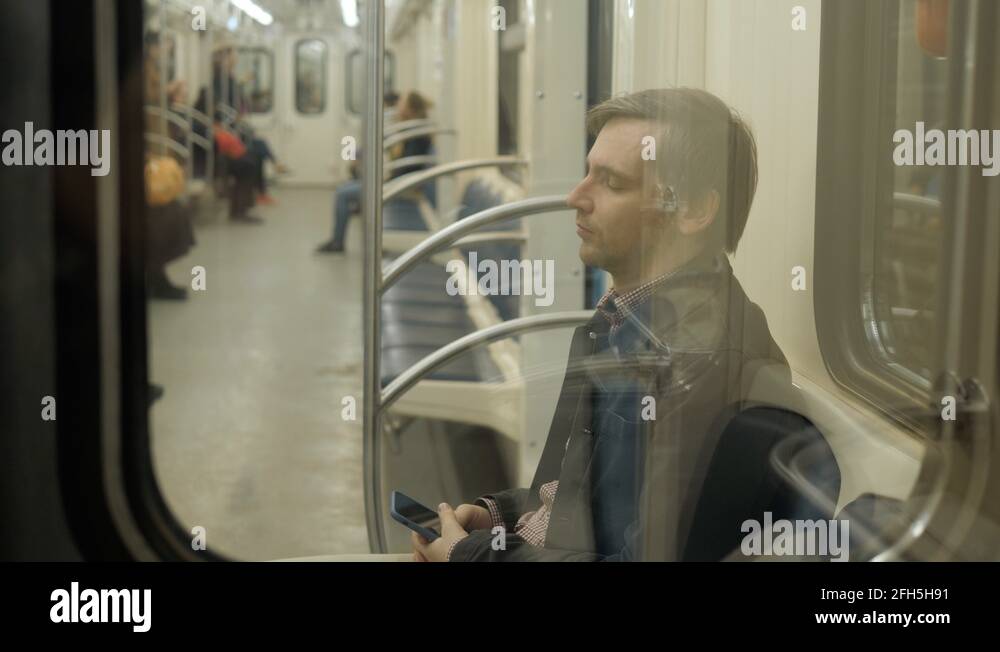 man sleeping in a underground Metro subway train. Tired worker student ...