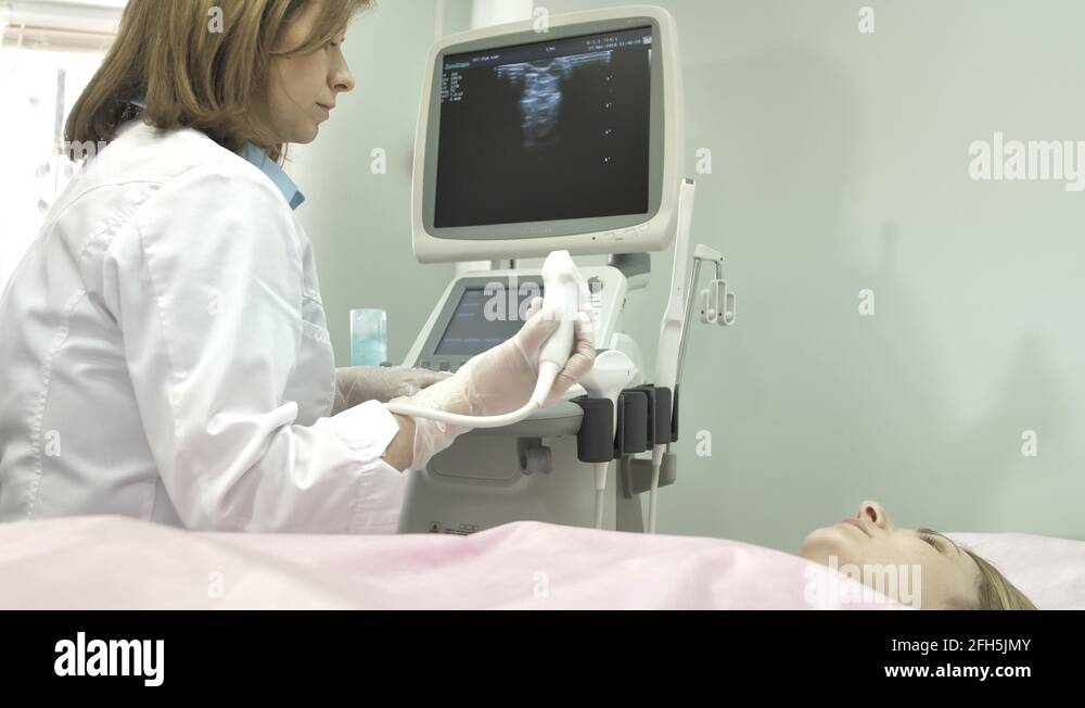 Female doctor examining the woman's neck using ultrasound scan Stock ...