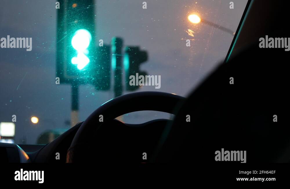 man chauffeur driving car through crossroad with green traffic light ...