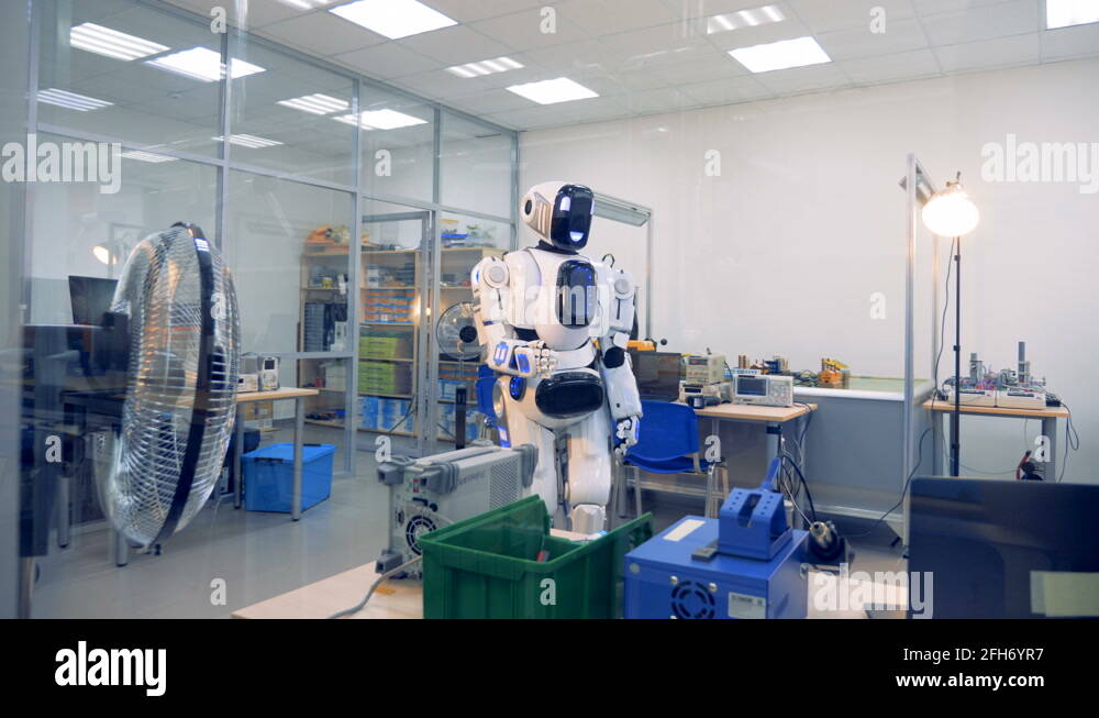 Engineering office room with a robot lifting its hand and bending ...