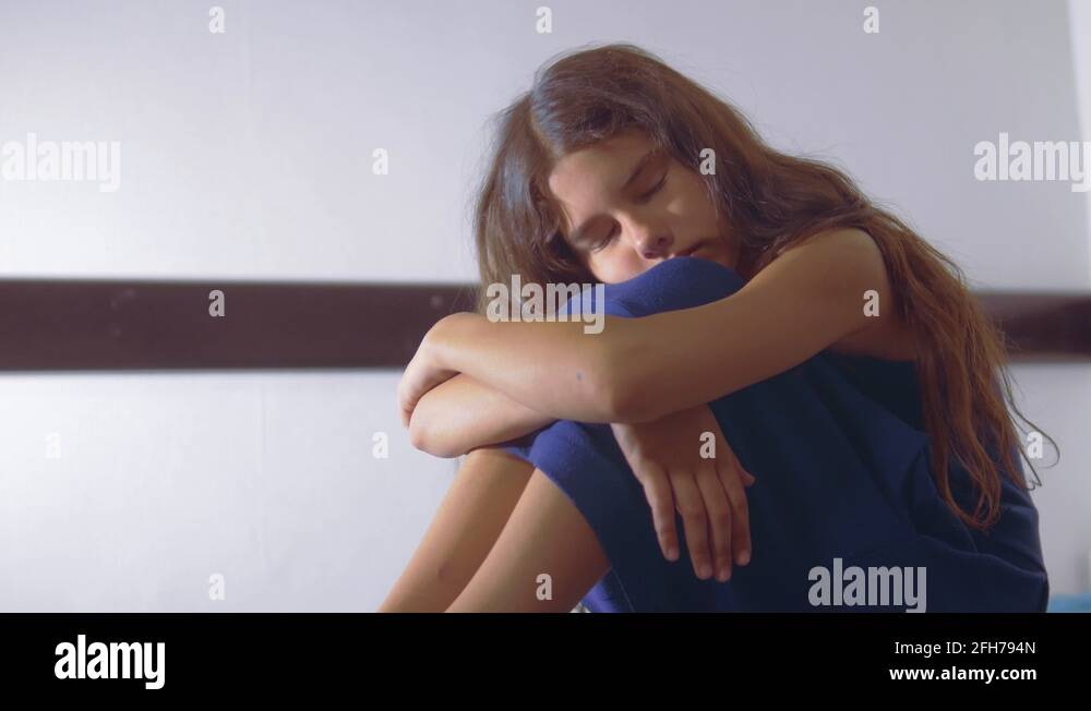 sad girl upset embraces her feet. is depressed and suicidal little ...