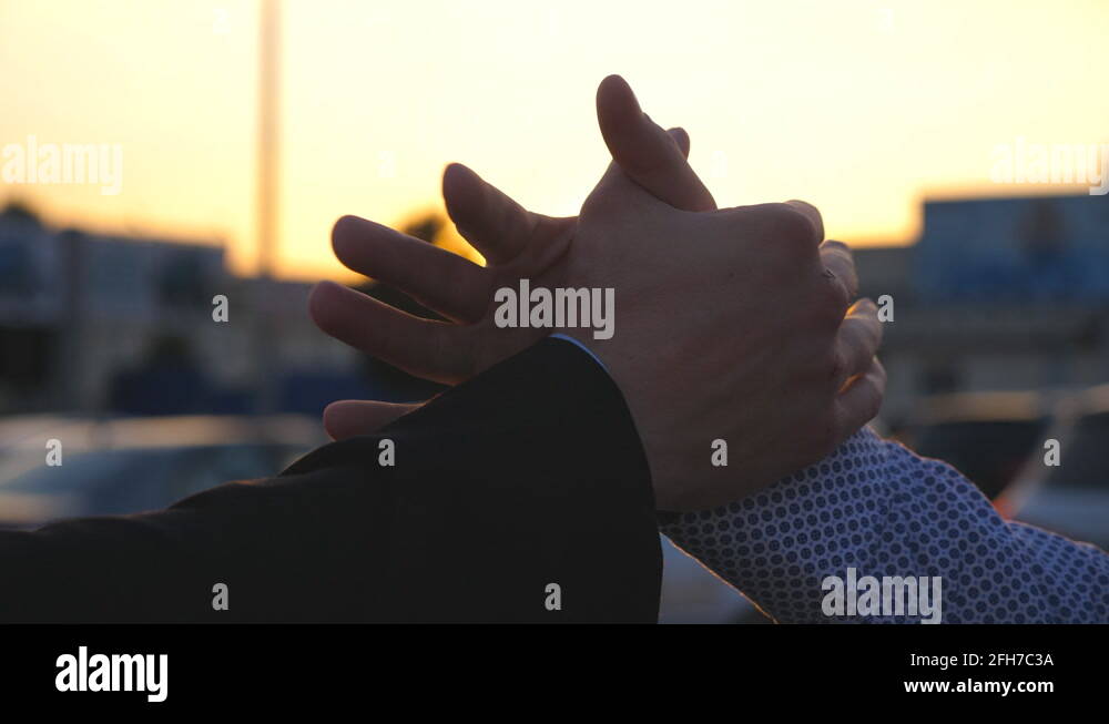 Two business men having firm friendly handshake outdoor with sun flare ...