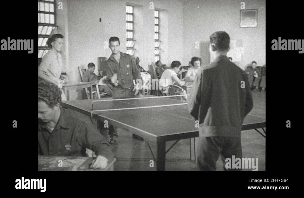 1940s: A nurse and a man play ping pong against two men, people sit ...