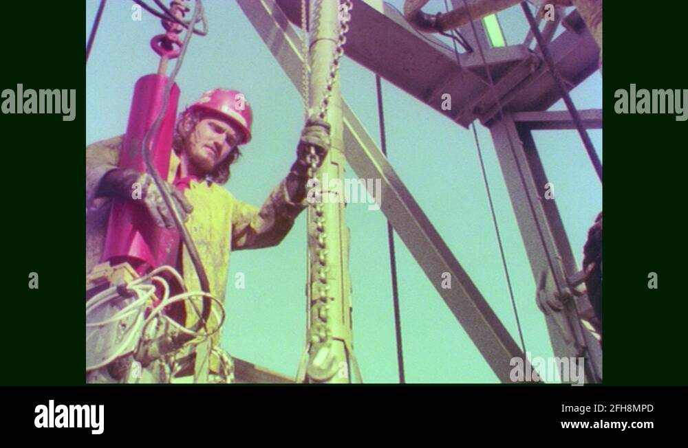 1970s: Men attach safety clamp to the drill pipe on top of the oil rig ...