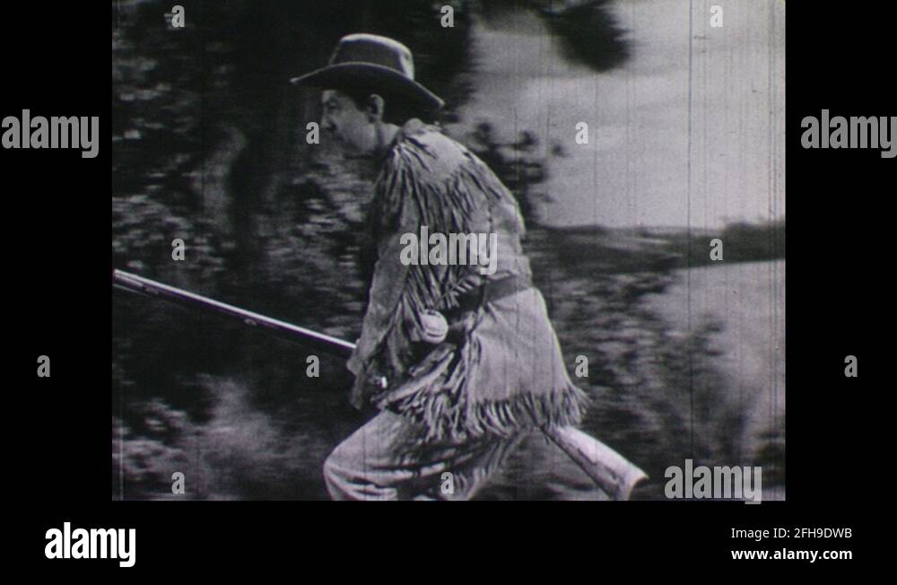 1940s: Man crouches and fires rifle. Native Americans on horseback ...