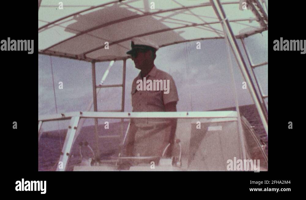 1960s: Captain pilots boat. Fishing boat speeds leaving wake Stock ...