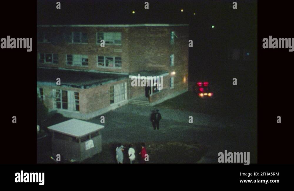 1970s: Police escort people out of building. Truck with flashing lights ...