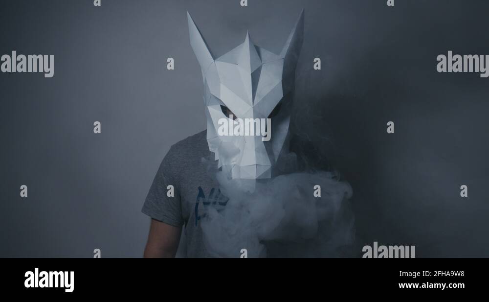 CINEMAGRAPH - Male wearing dragon head paper craft mask exhaling smoke ...
