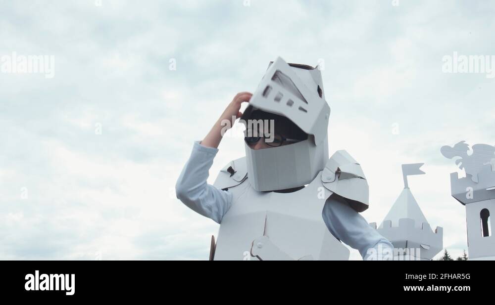 Kid boy wearing cardboard medieval knight armor costume draws a sword ...