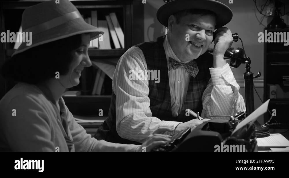 1940s newspaper reporter on the phone while the other reporter types ...