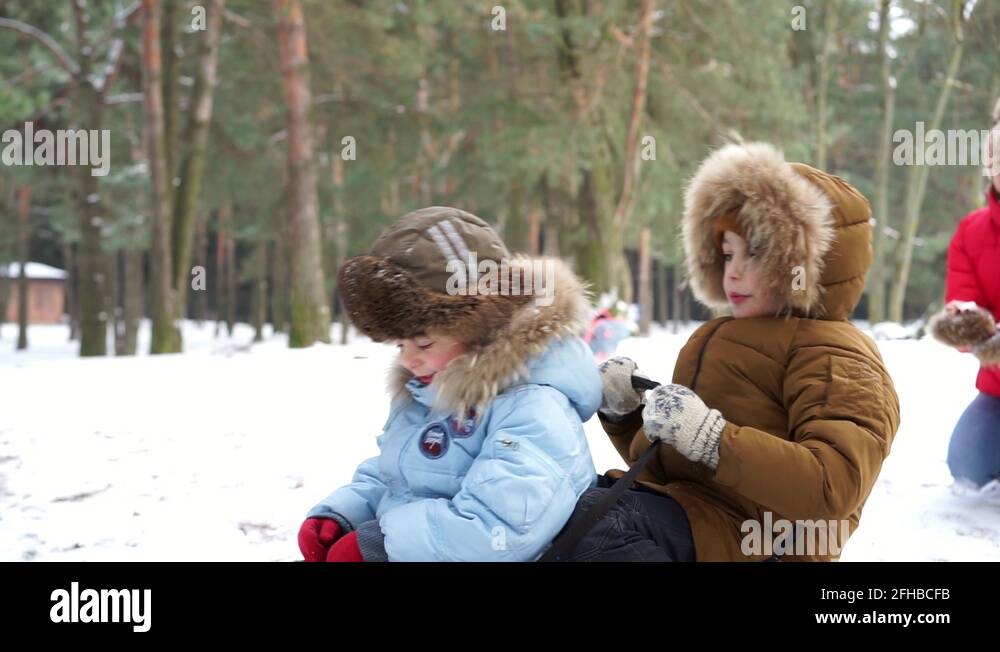 Two boys on sledge riding down and their mother drop snow ball Stock ...