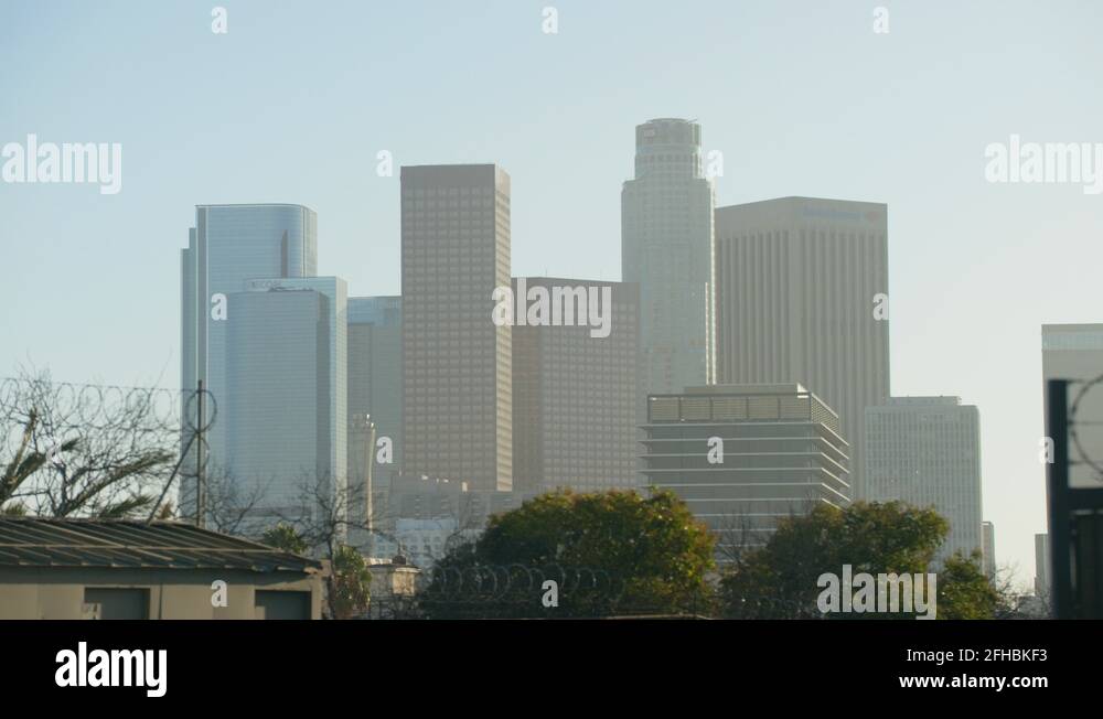Skyscrapers of Los Angeles seen behind a barb wire sliding gate ...