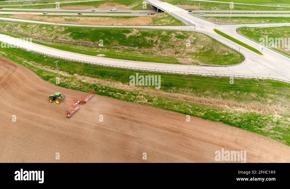 Tractor working fields next to busy highway Stock Video Footage - Alamy