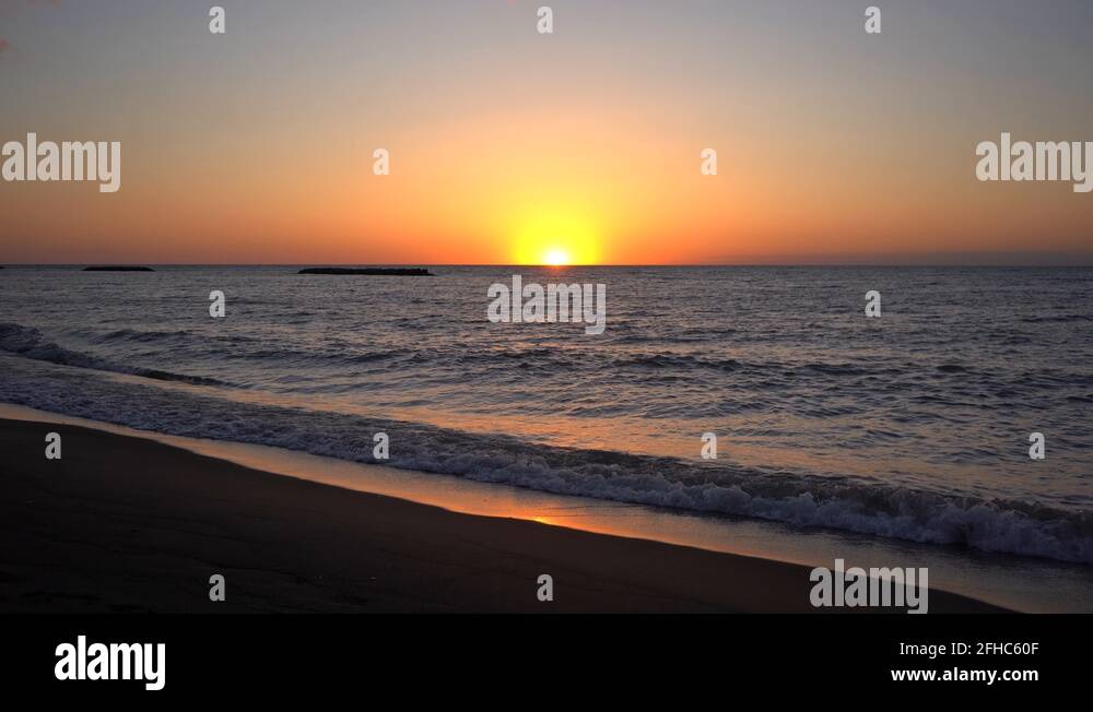 A beautiful sunset over a great lake. Waves crashing on the shore as ...