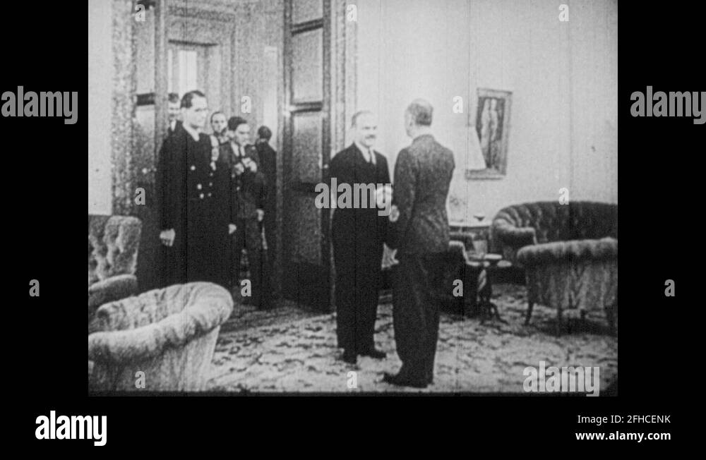 1930s: Soviet and Nazi emissaries shake hands, sit down in room. Man ...