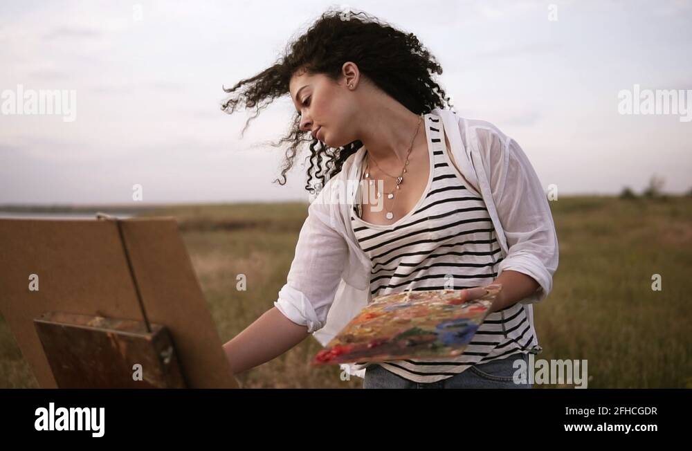 Beautiful curly woman artist concentrated on painting process. Working ...
