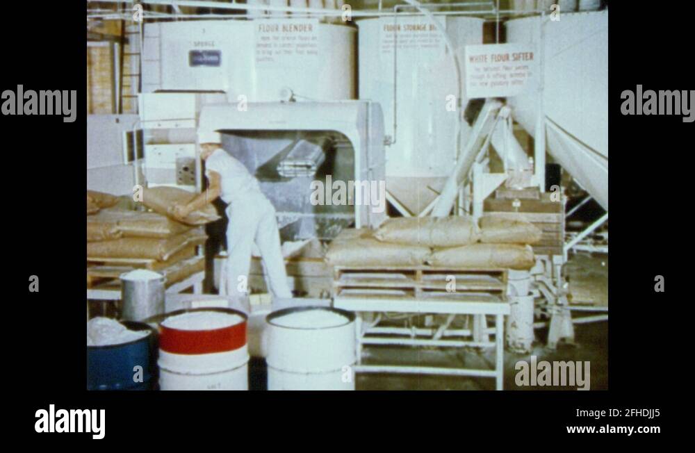 1950s: Man lifts sack off table, opens sack, pours contents into ...