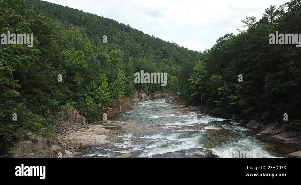 Flying down the river revealing the rushing waters and rocky formations ...