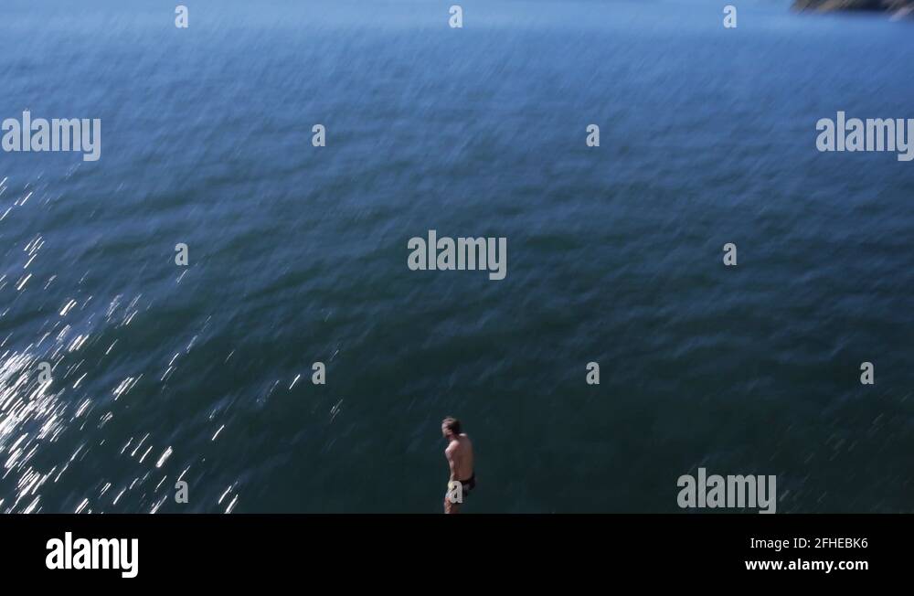 A man swings from a rope off a cliff into the ocean Stock Video Footage ...