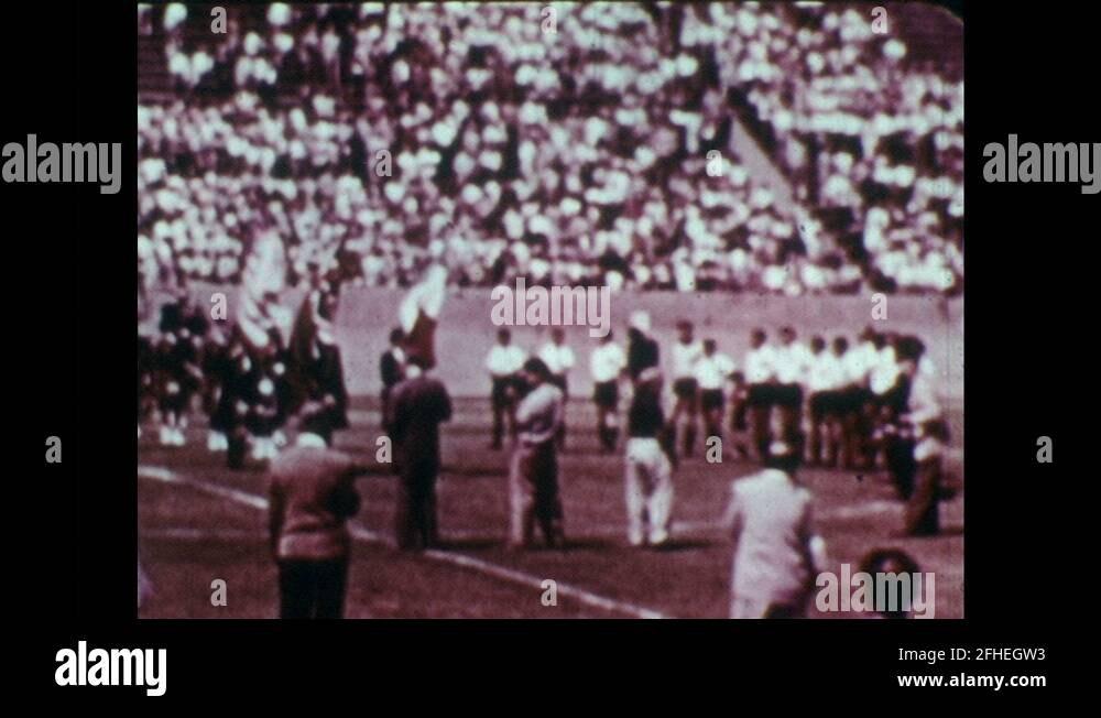 1970s: UNITED STATES: men play football match on pitch. Flags waved on ...