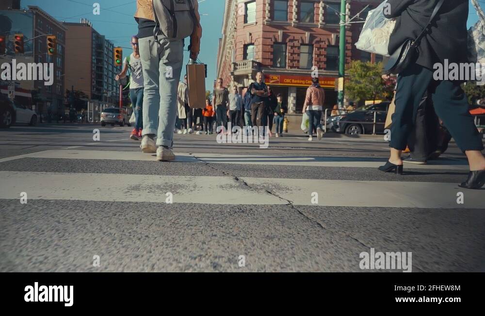 Low angle shoting through a crowd of pedestrians crossing the street in ...