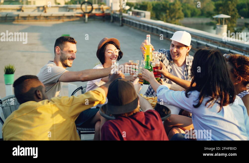 Happy men and women are clinking glasses and bottles with drinks then ...