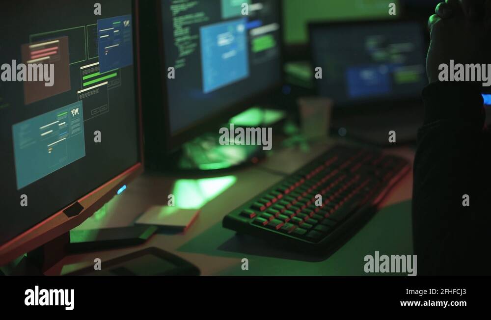 Hacker With Hoodie Working With Multiple Screens And Hacking Systems