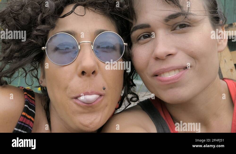 two happy, smiling women, girls making a bubble from chewing gum ...