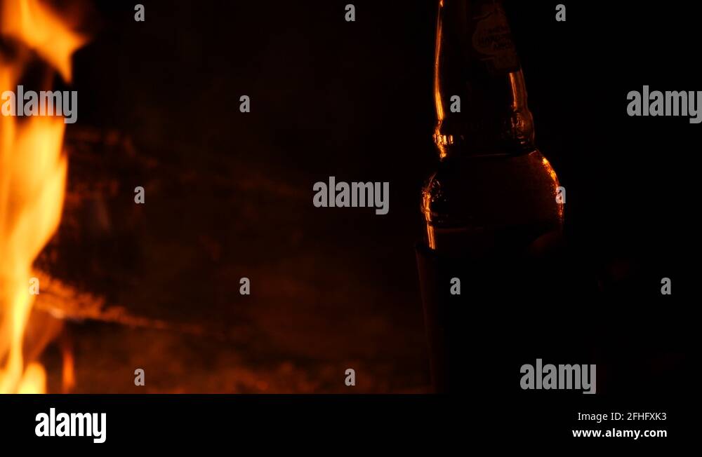 Beer bottle by a fire at night Stock Video Footage - Alamy