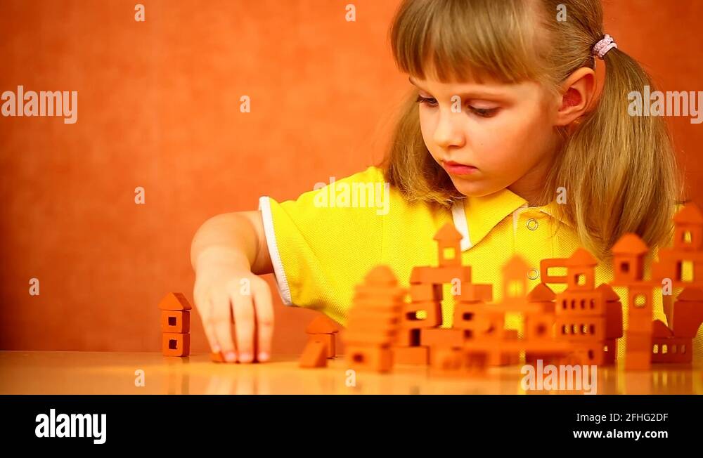 a dreamy cute little girl builds small houses and towns from small ...