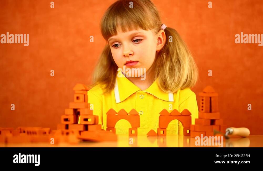 a dreamy cute little girl builds small houses and towns from small ...