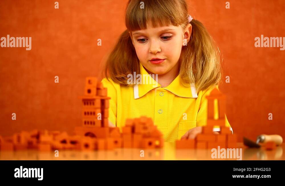 a dreamy cute little girl builds small houses and towns from small ...
