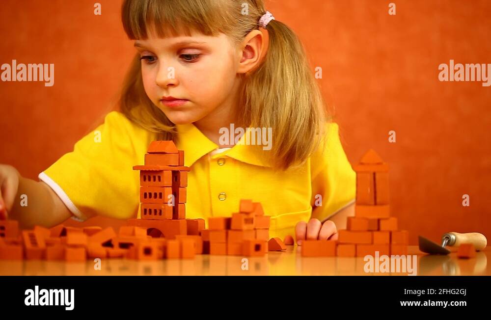 a dreamy cute little girl builds small houses and towns from small ...