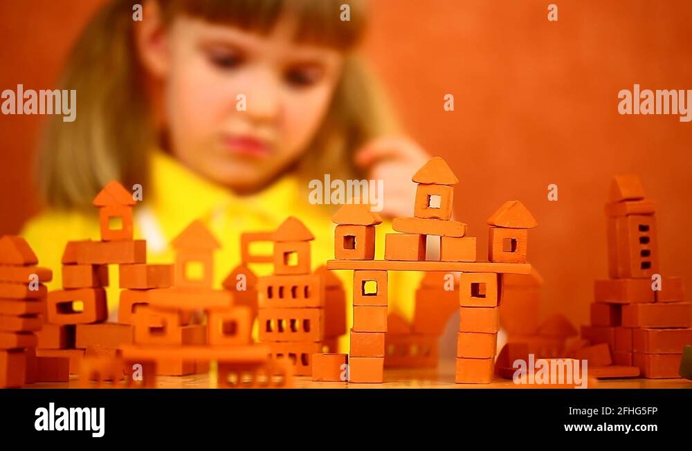 a dreamy cute little girl builds small houses and towns from small ...