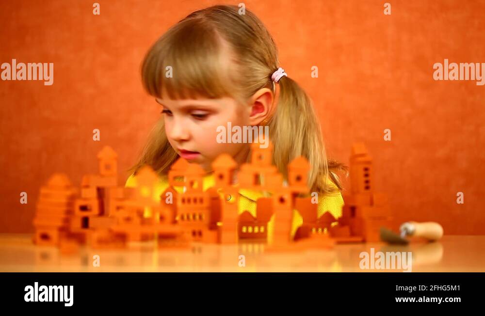 a dreamy cute little girl builds small houses and towns from small ...