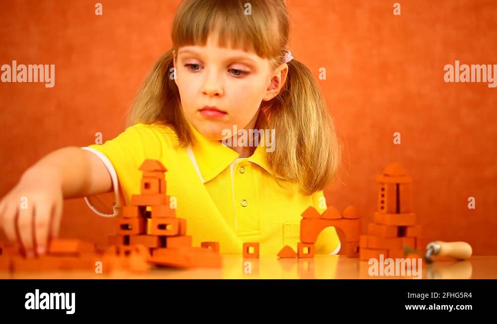 a dreamy cute little girl builds small houses and towns from small ...