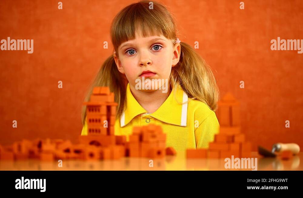a dreamy cute little girl builds small houses and towns from small ...