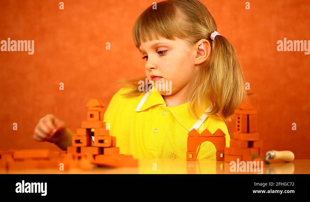 a dreamy cute little girl builds small houses and towns from small ...