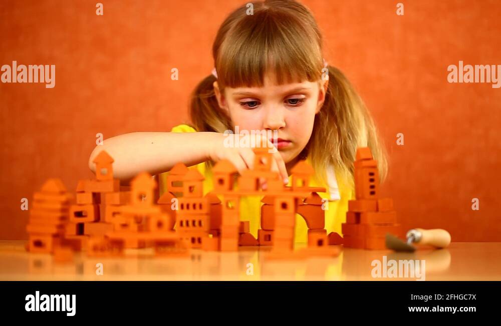 a dreamy cute little girl builds small houses and towns from small ...