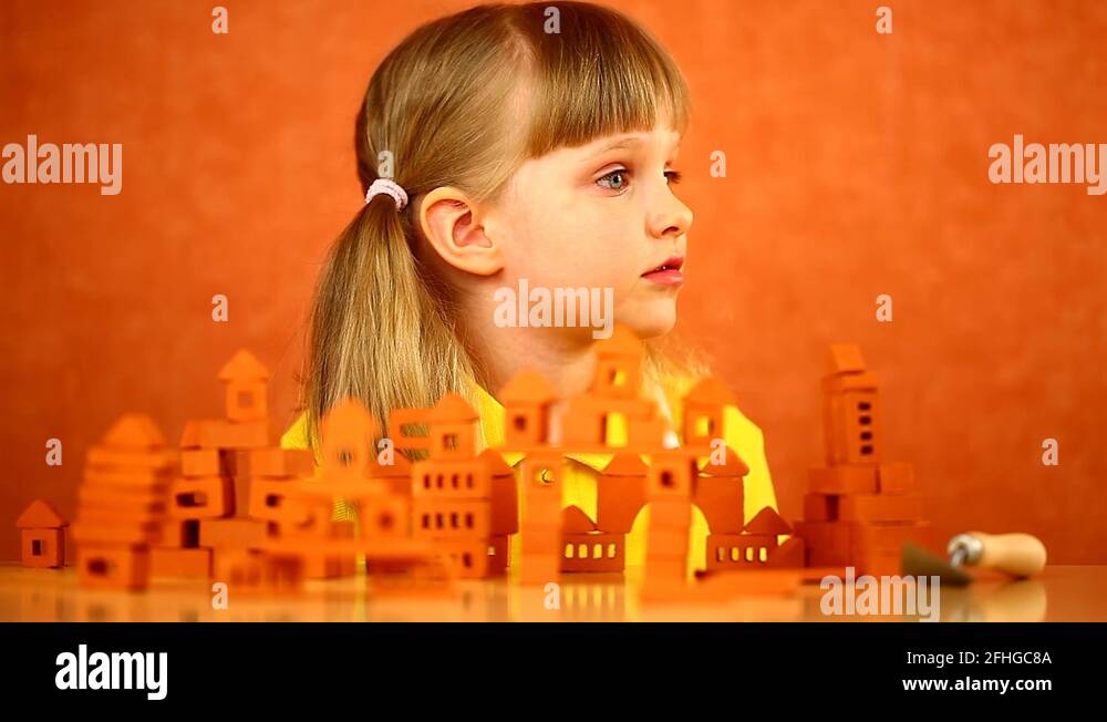 a dreamy cute little girl builds small houses and towns from small ...