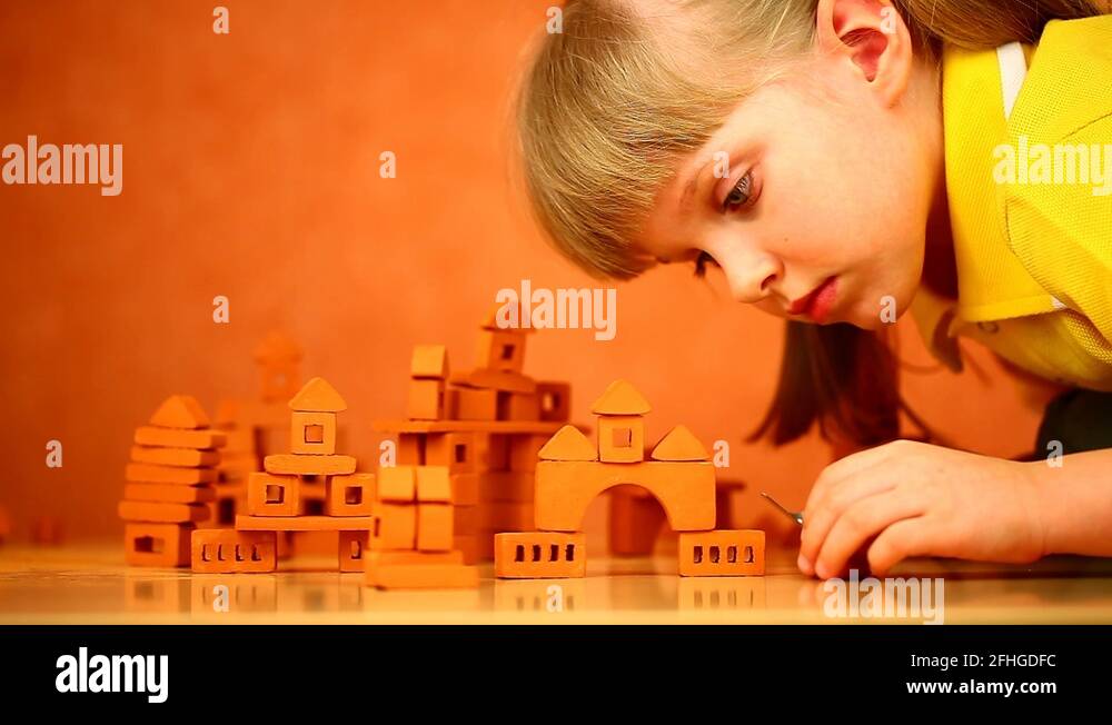 a dreamy cute little girl builds small houses and towns from small ...