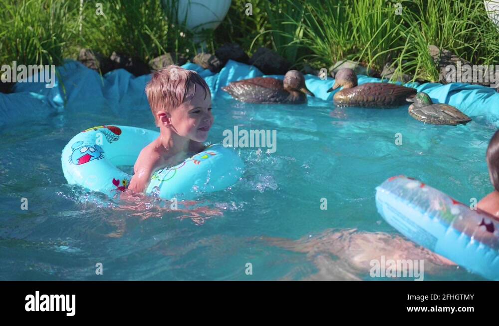 Two small children swim in a small pond. Brother and sister laughing ...