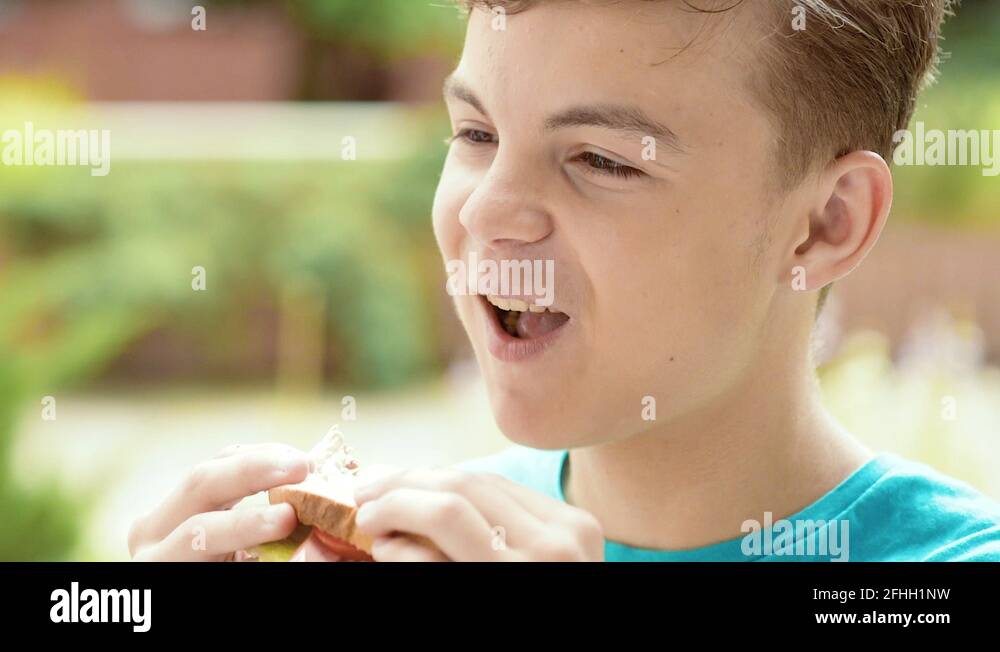 Teen boy eating sandwich Stock Video Footage - Alamy
