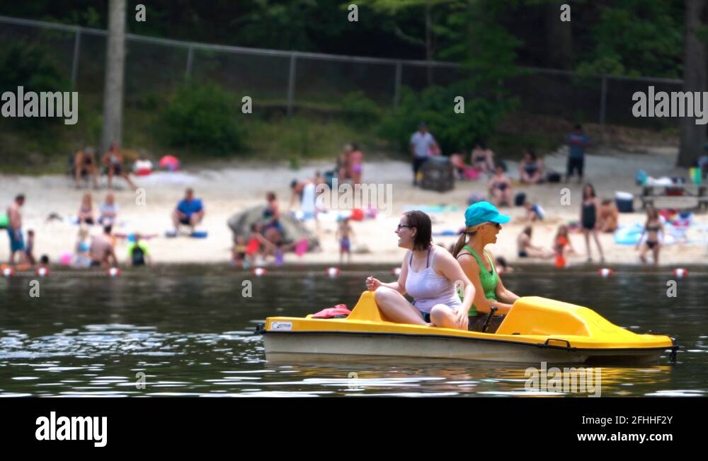 Two laughing women in a peddle boat being splashed by two boys on ...