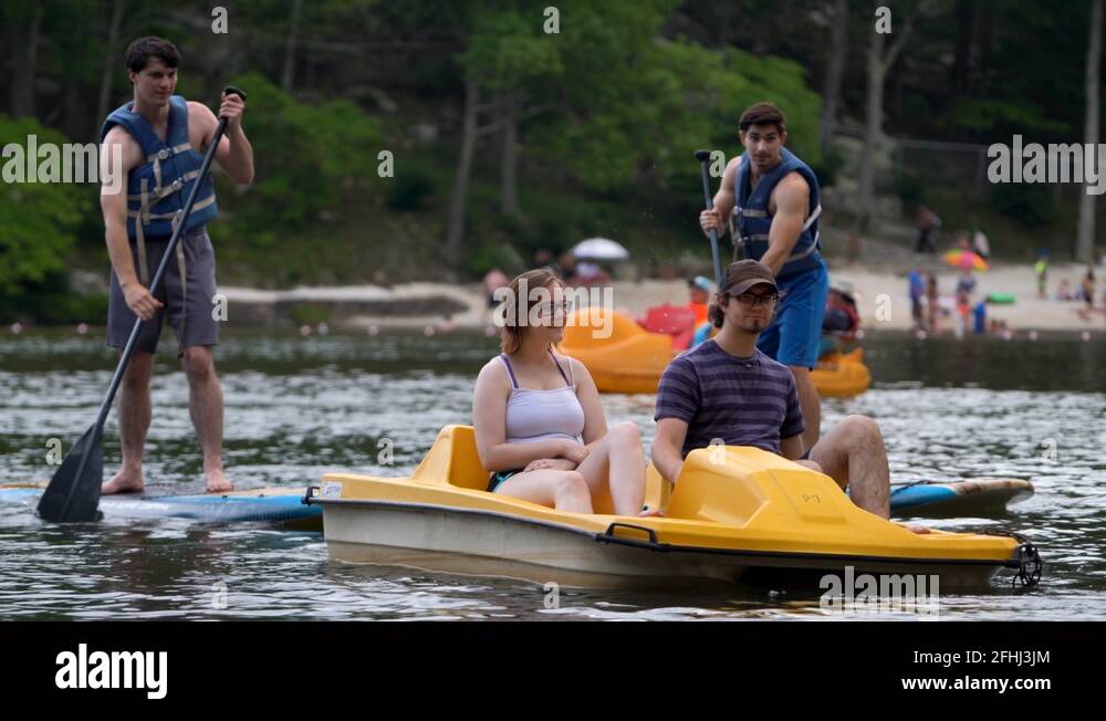 Two boys on paddle boards start a splash battle with a couple in a ...