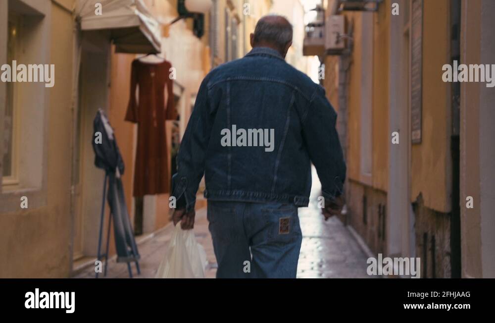 Old man dressed in denim walking down alley way alone Stock Video ...