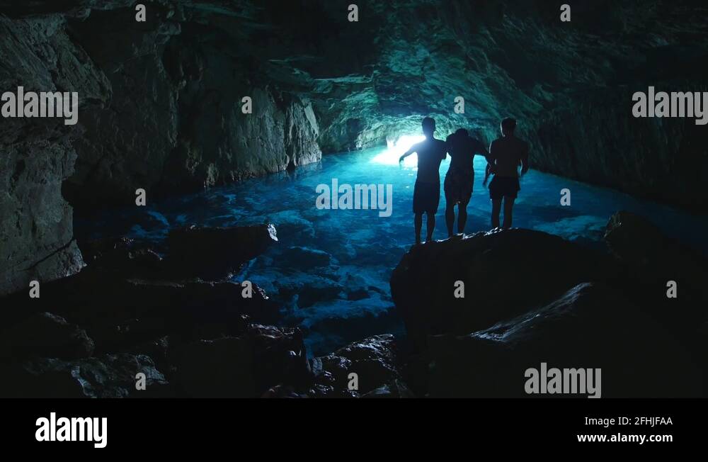 Three man jumping in the water inside a blue cave in the calanques ...